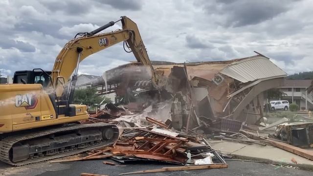 Гусеничный экскаватор разрушает торговое здание
