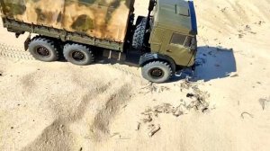 Модель бортового КАМАЗа с тентом едет по песку