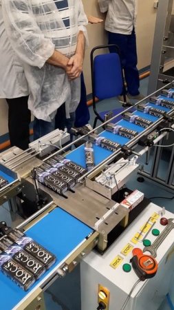 Система разделения потоков коробочек зубных паст с быстрого конвейера на два меделнных по 3 штуки