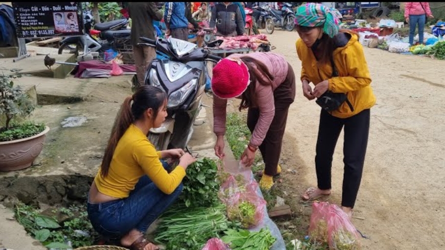 Дуонг собирает дикий лук , цветы папайи для продажи на рынке.