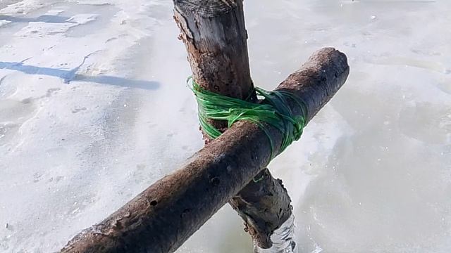 Самодельное крепление из двух деревянных бревен, скрепленных зеленой пластиковой лентой