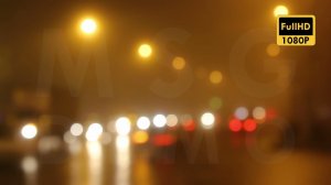 Blurred lights of city in fog and cars on road.